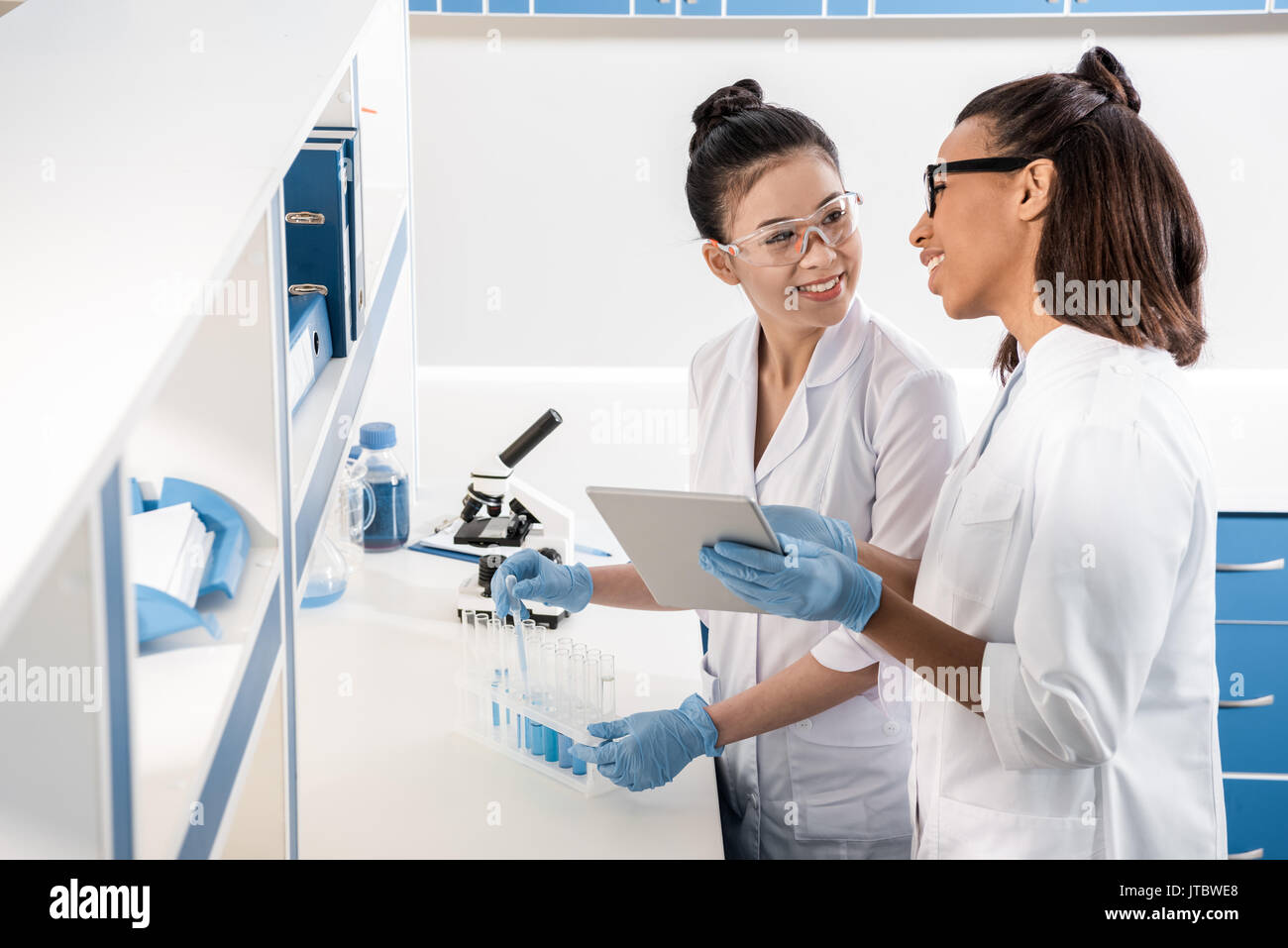 Professional young scientists using digital tablet while making ...