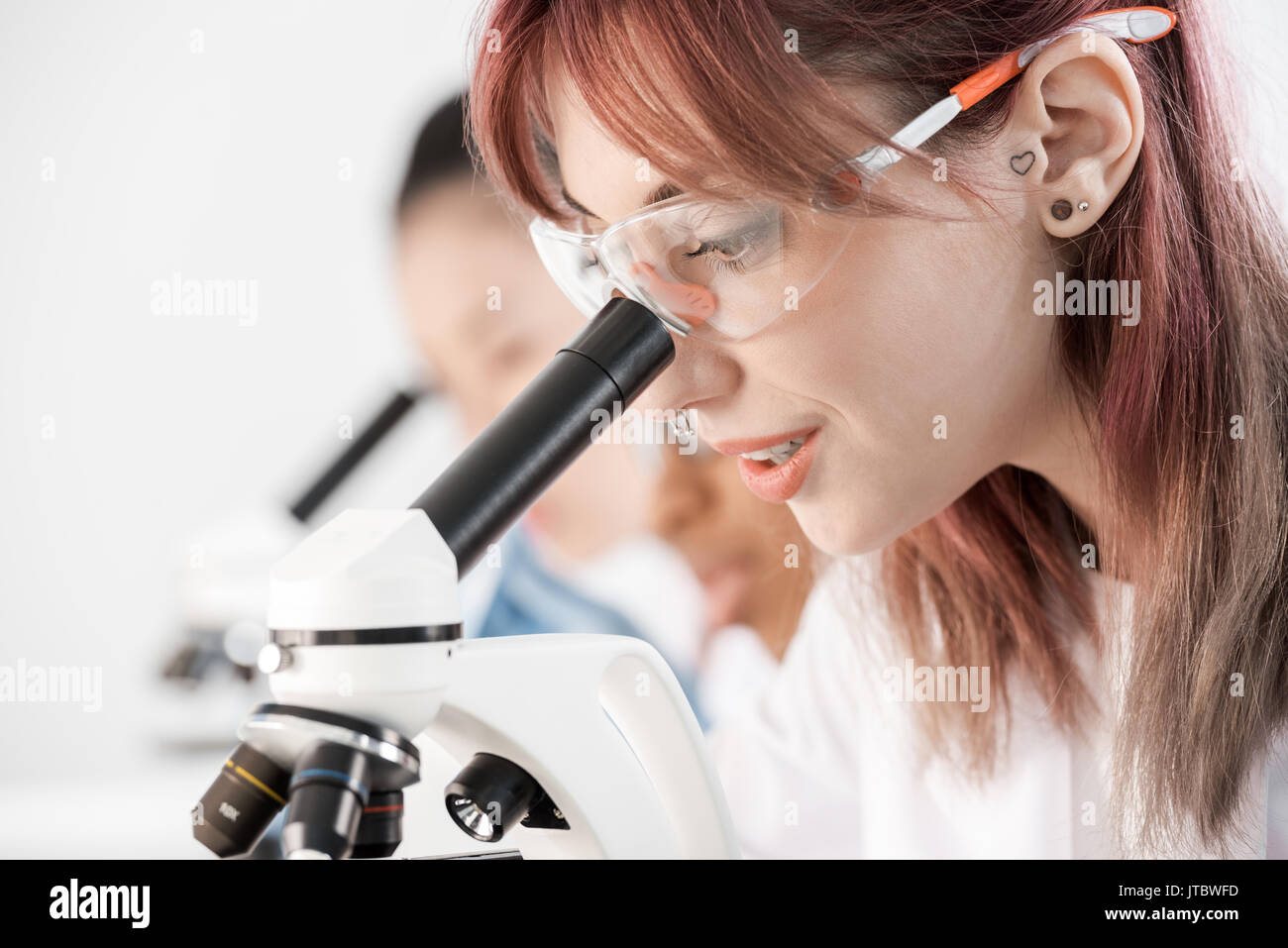 Side view of young scientist in protective goggles working with ...
