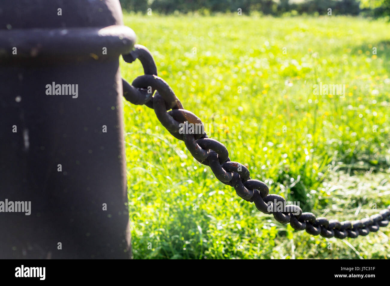 pillar with black iron chain on grass background. industrial, nature ...