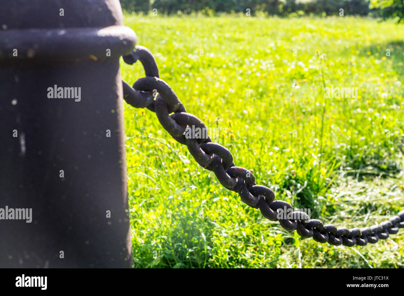 pillar with black iron chain on grass background. industrial, nature ...