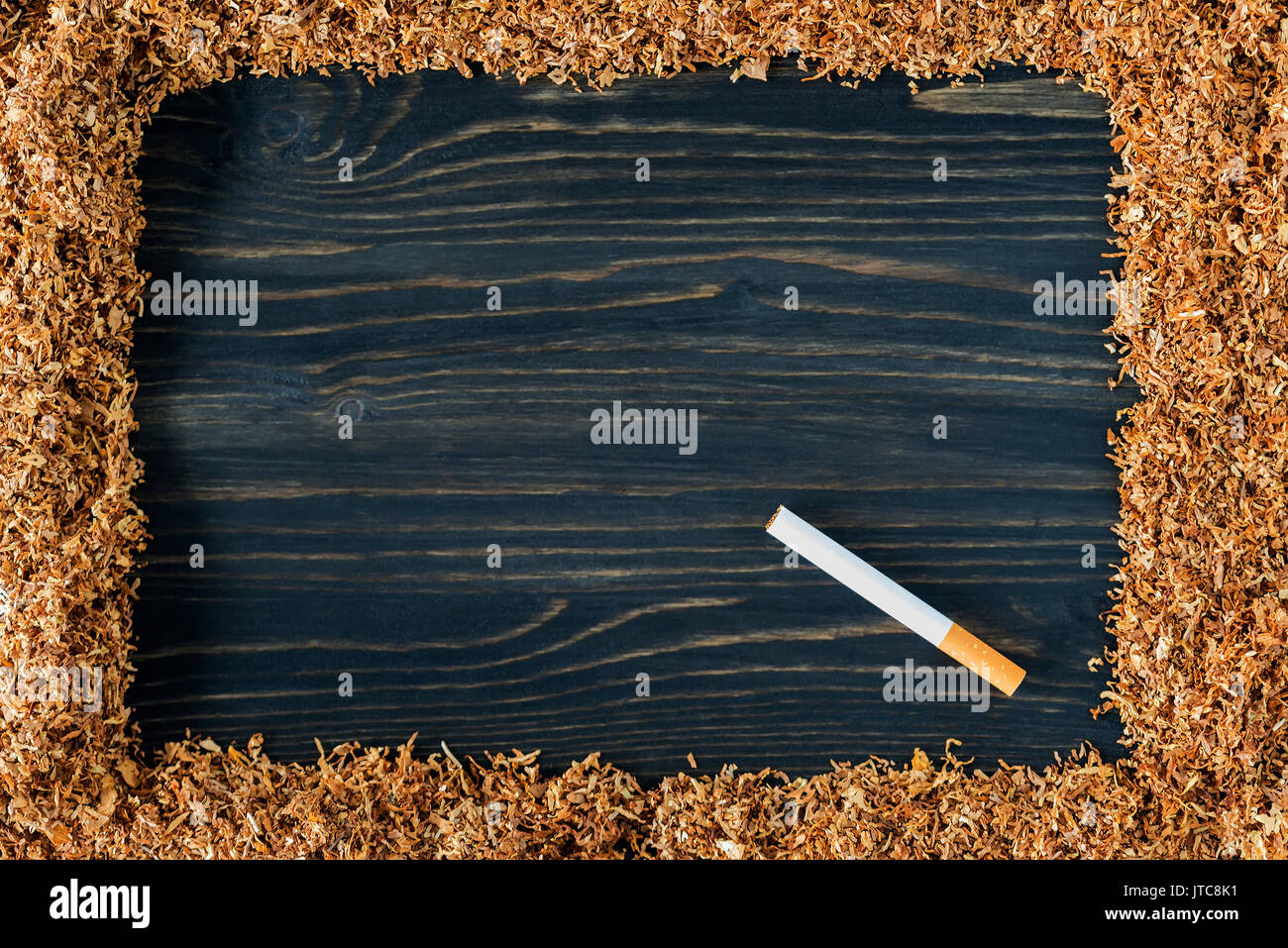 Tobacco still life, cigarette on a wooden table in a frame of tobacco ...