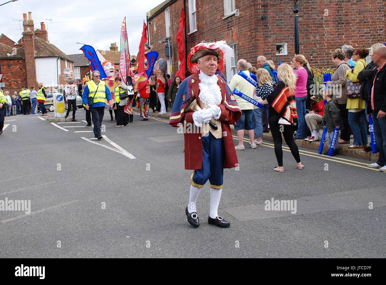 Rex Swain, Town Crier, walks past people lining the street at an ...