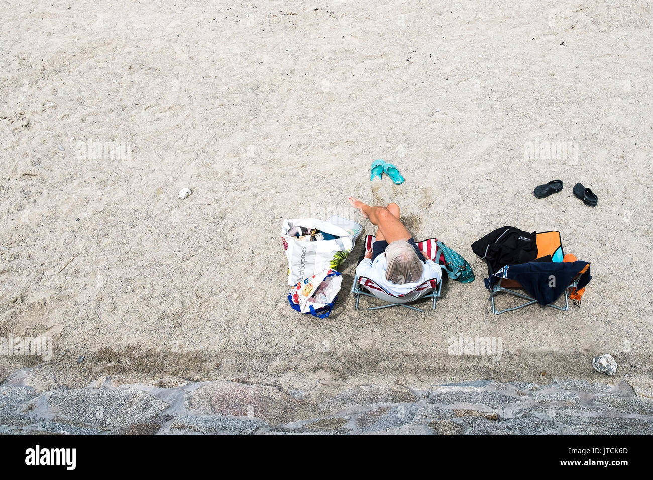 An overhead view of a female holidaymaker relaxing on the beach at ...