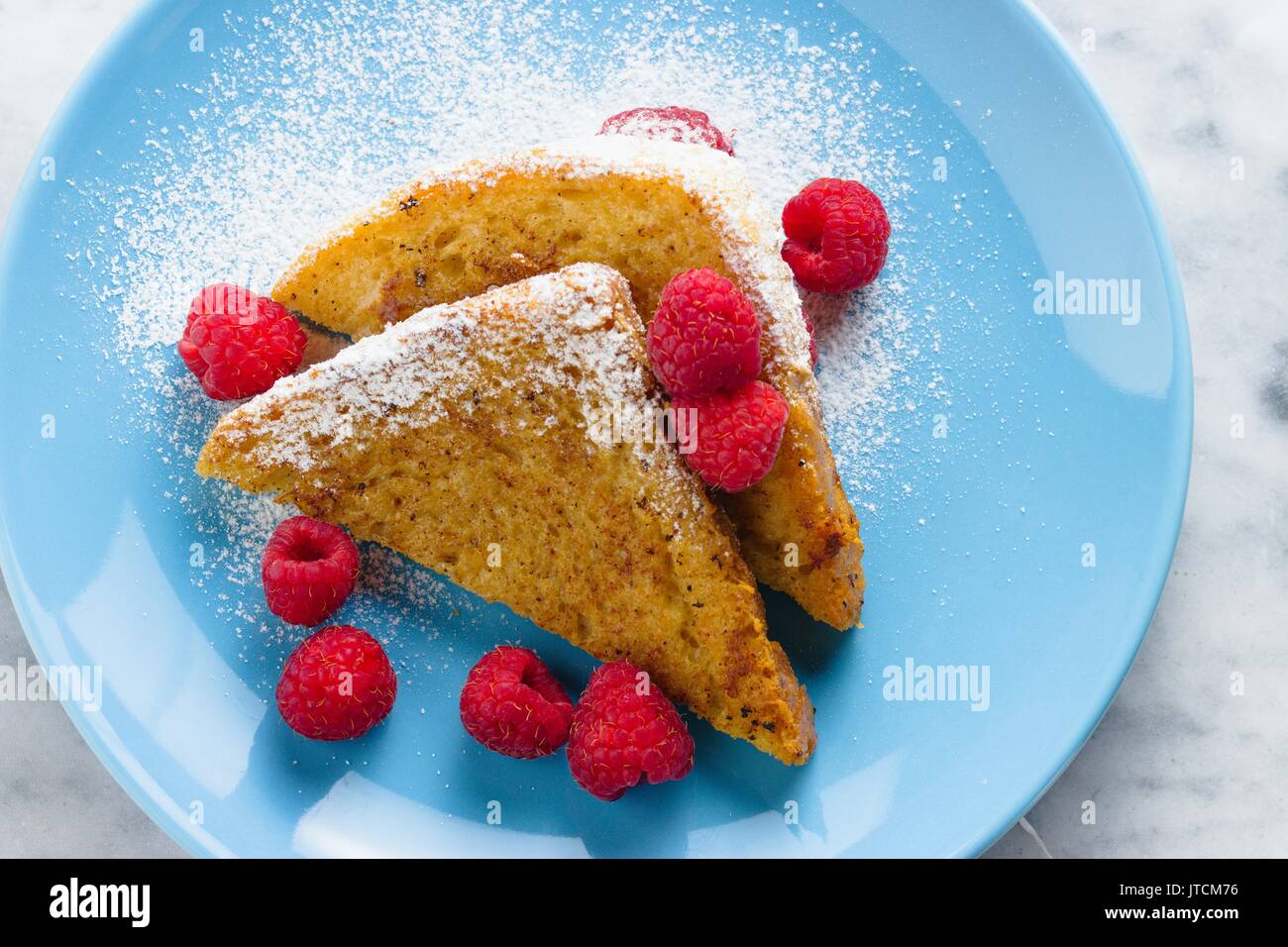 Top down view on two french toast triangles with sugar and raspberries ...
