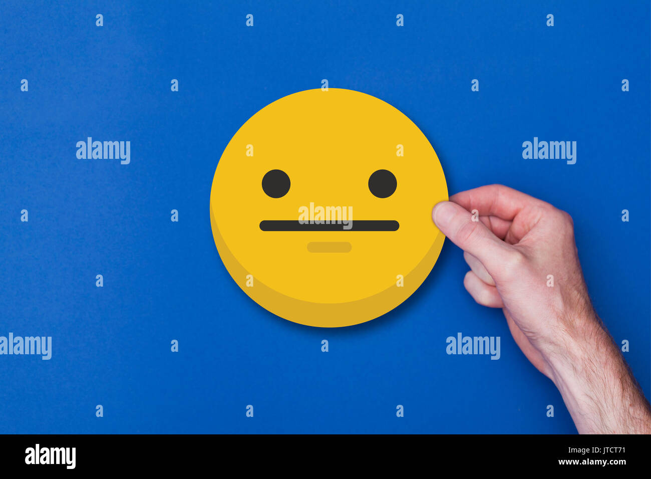 Male hand holding a emoji emoticon smiley head icon Stock Photo - Alamy