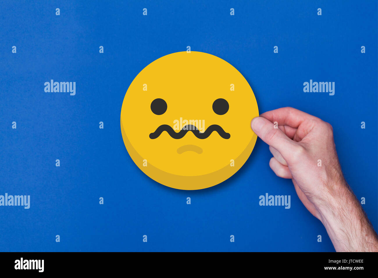 Male hand holding a emoji emoticon unhappy smiley head icon Stock Photo ...