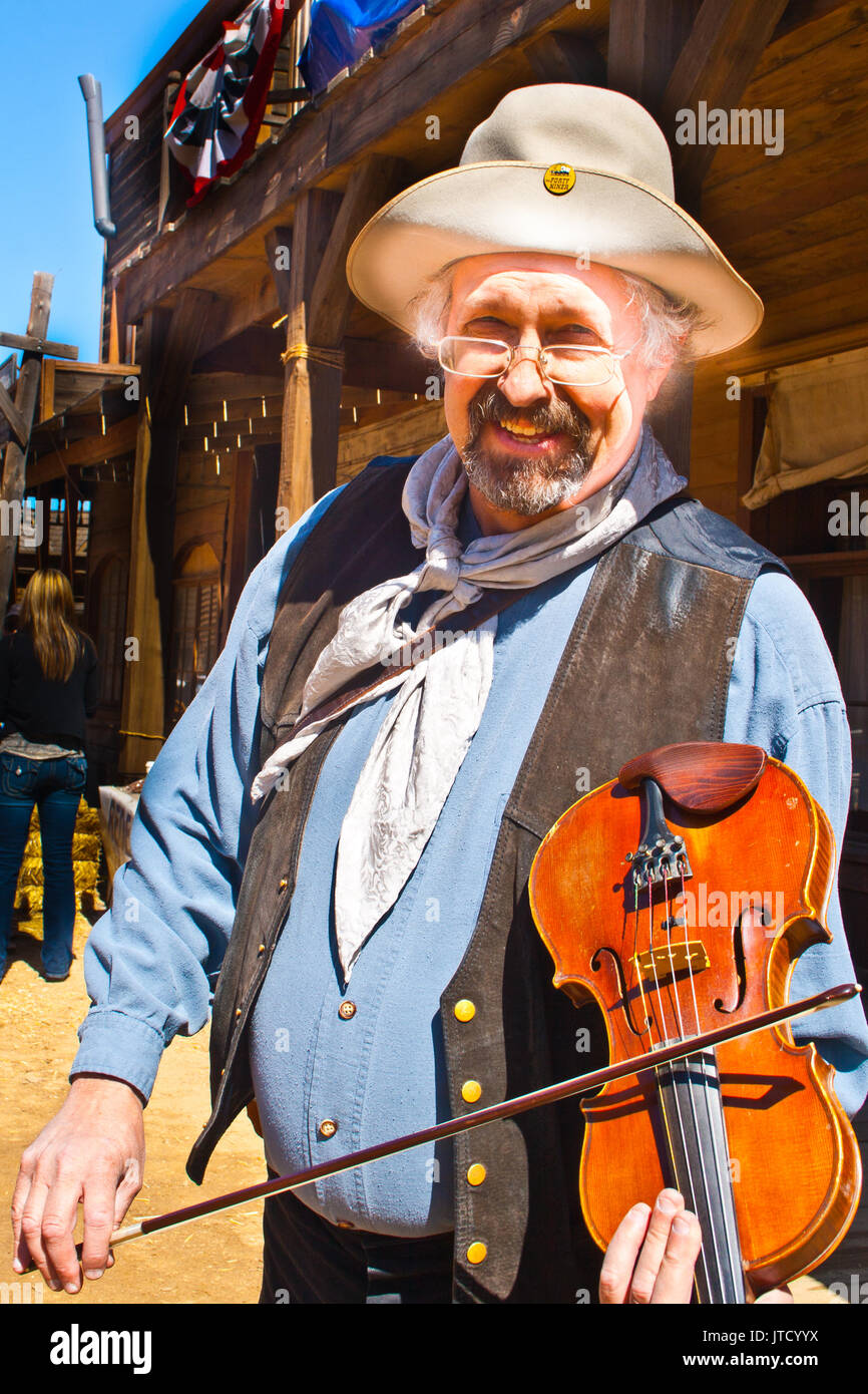 Cowboy dressed as a "Gold Country Fiddler & Minstrel", plays his fiddle ...