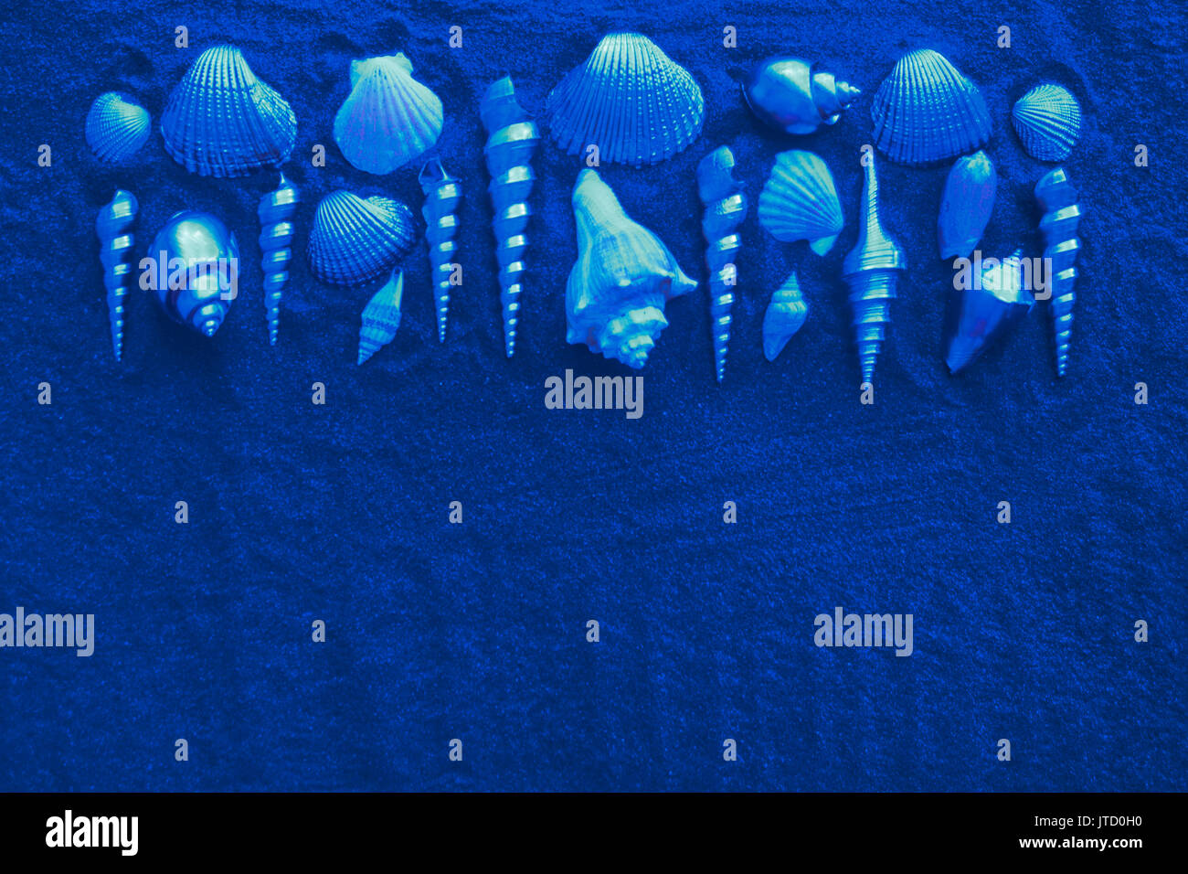 Aqua-blue colored sea shells form patterns on dark blue sand Stock ...