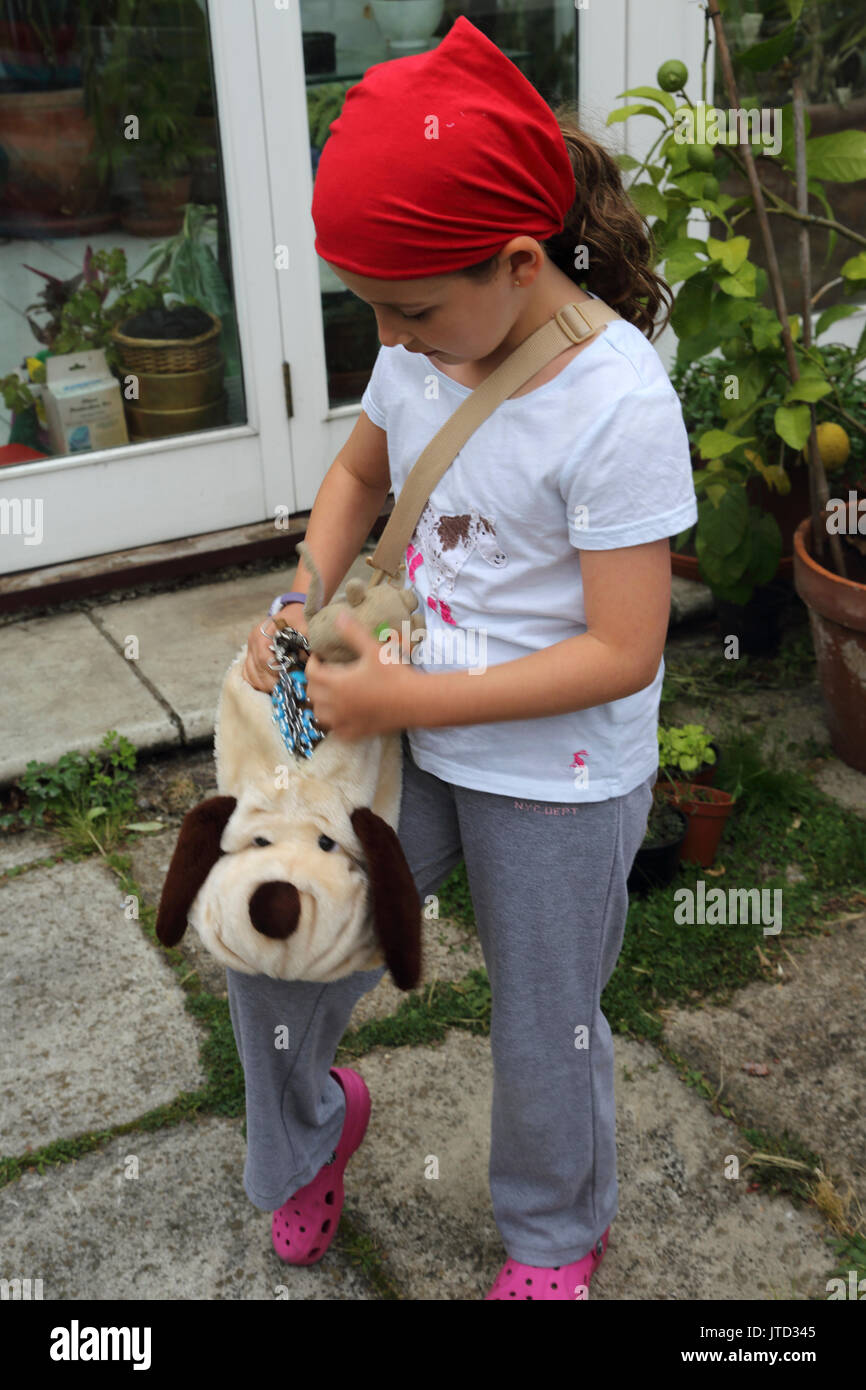 Young girl carrying soft toys in a dog shoulder bag Surrey England ...