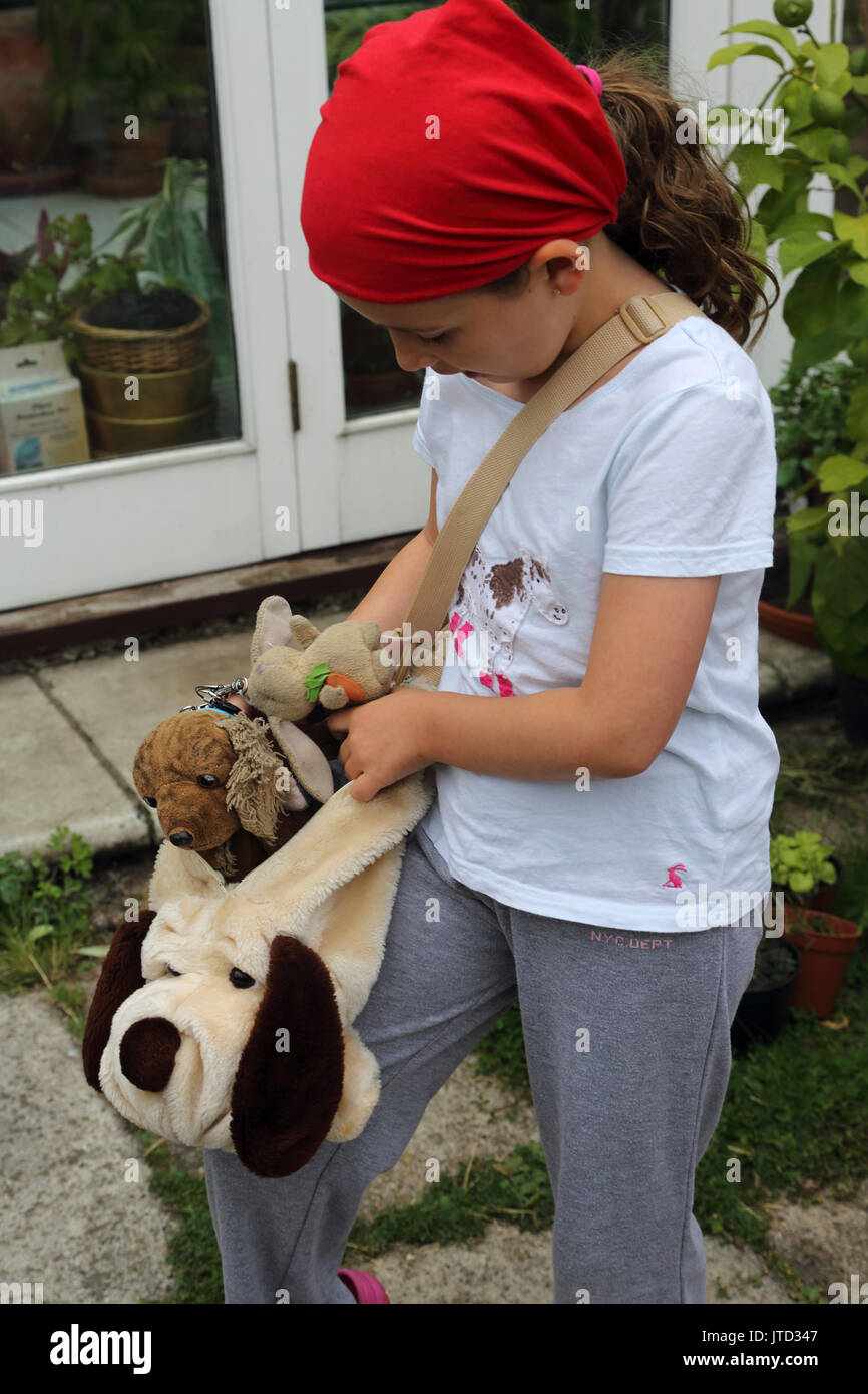 Young girl carrying soft toys in a dog shoulder bag Surrey England ...
