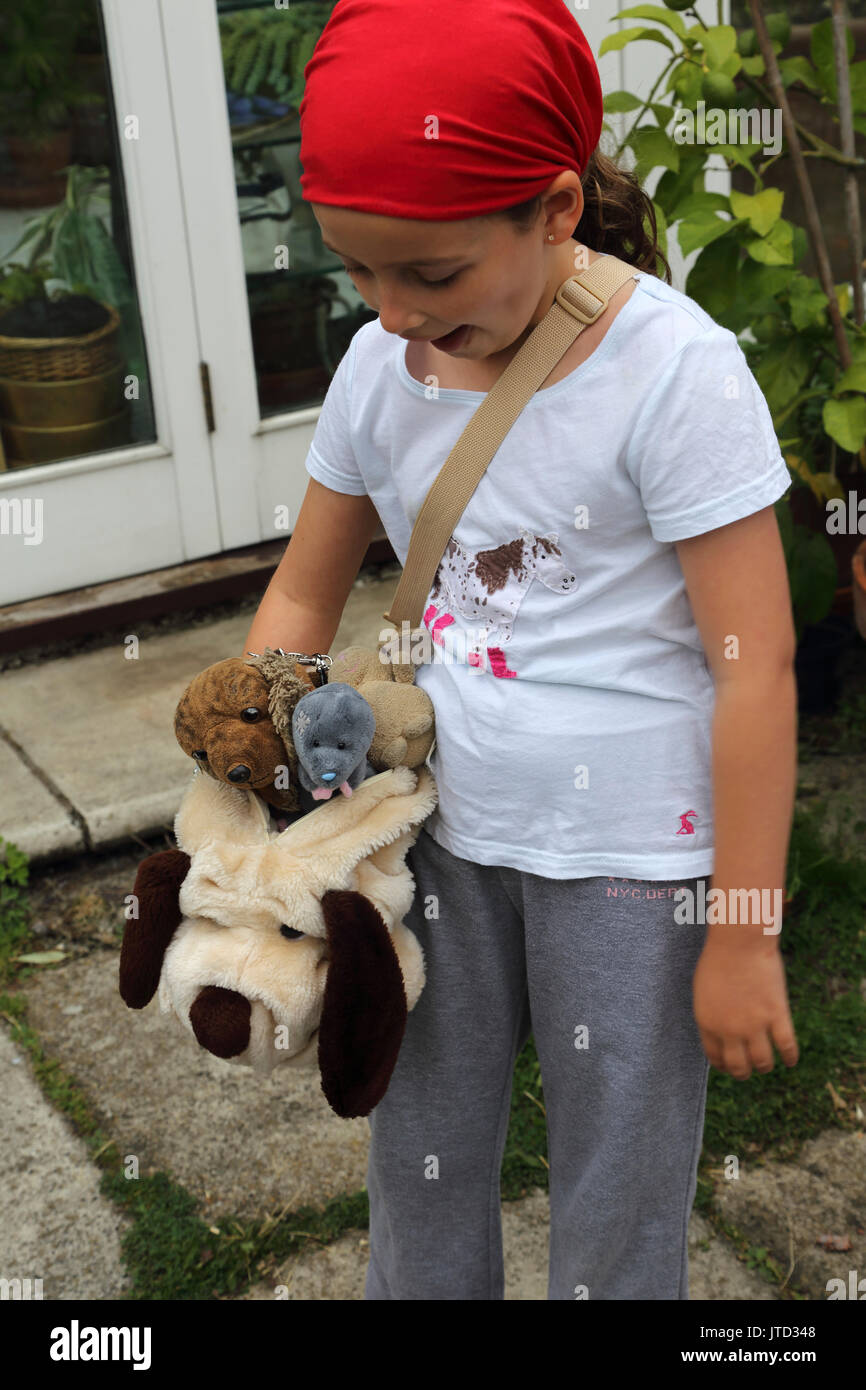 Young girl carrying soft toys in a dog shoulder bag Surrey England ...