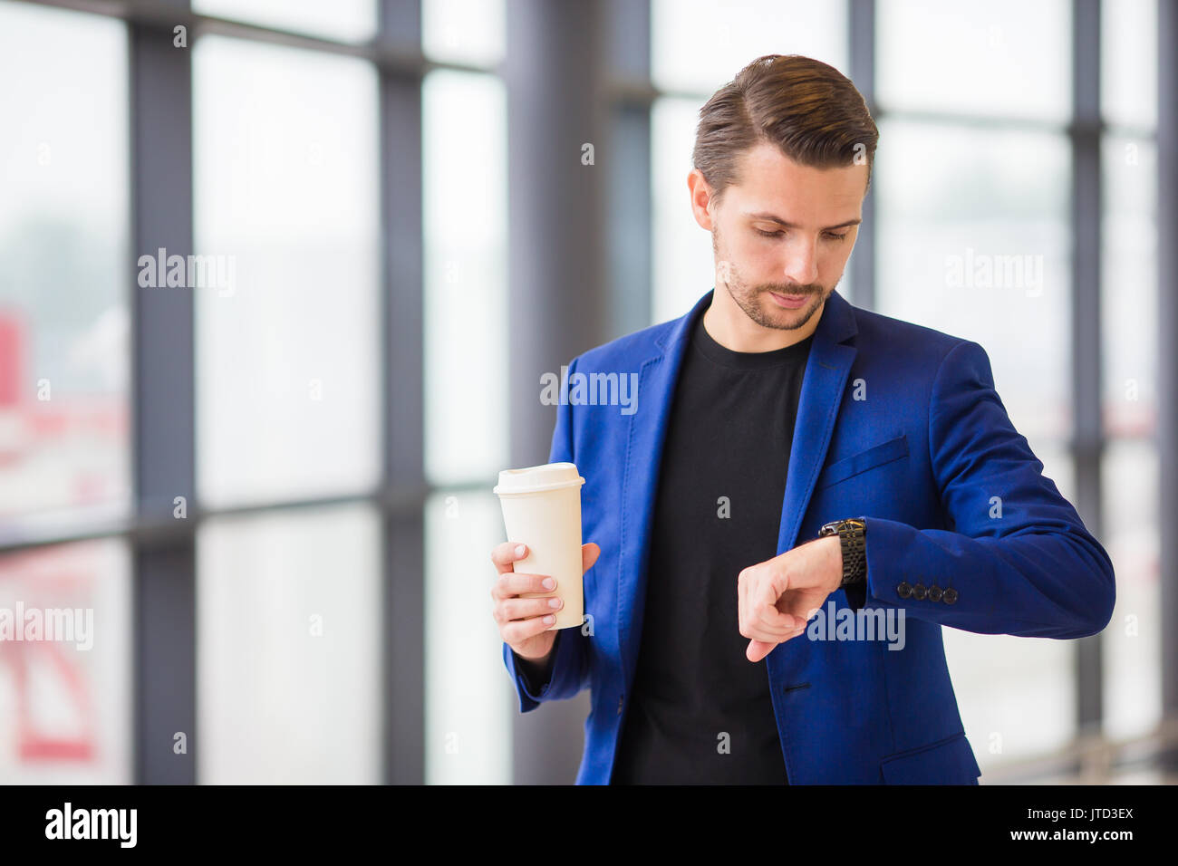 Urban man with coffee inside in airport. A young man is late for a ...