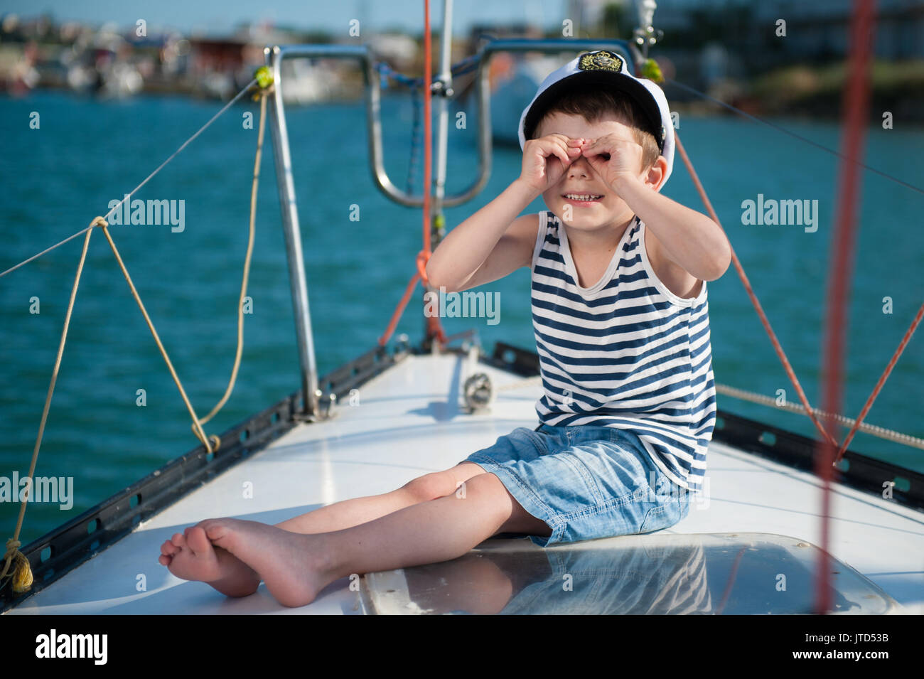 happy kid captain sitting on luxury boat with sea background behind ...