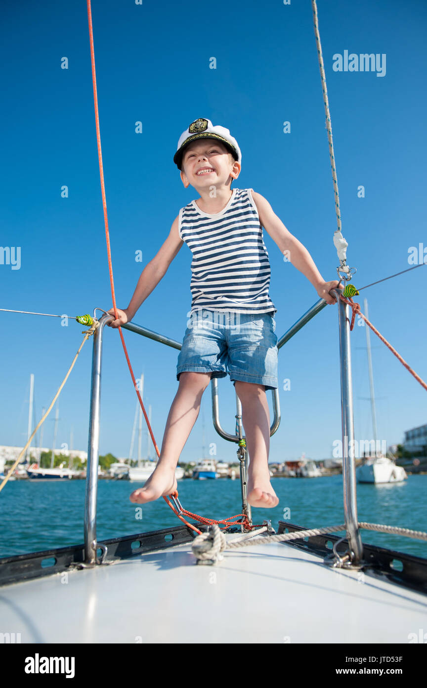 happy small boy wearing captain cap on luxury white yacht in summer day ...