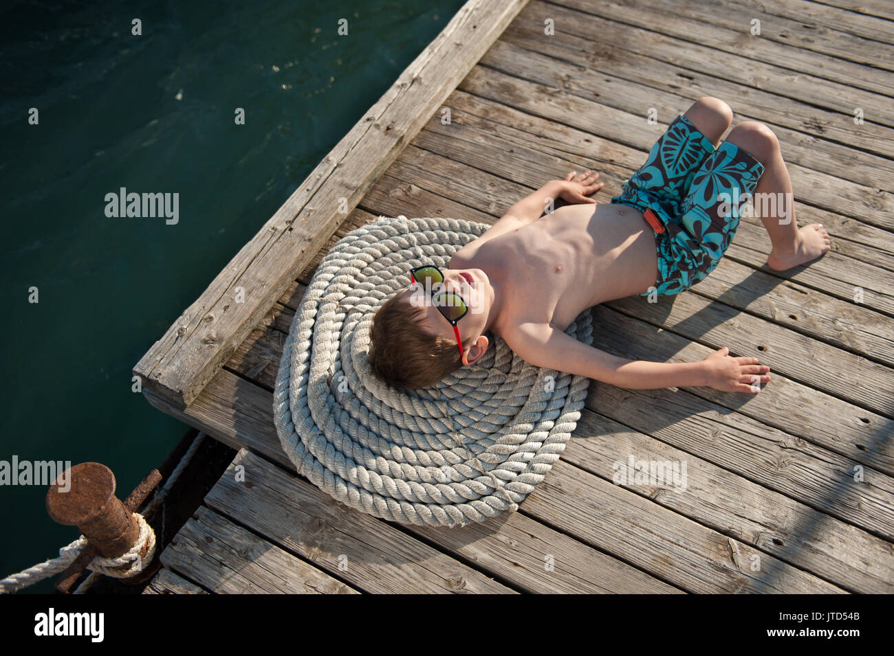 cute little kid sunbathing lying on rope and wooden pier Stock Photo ...