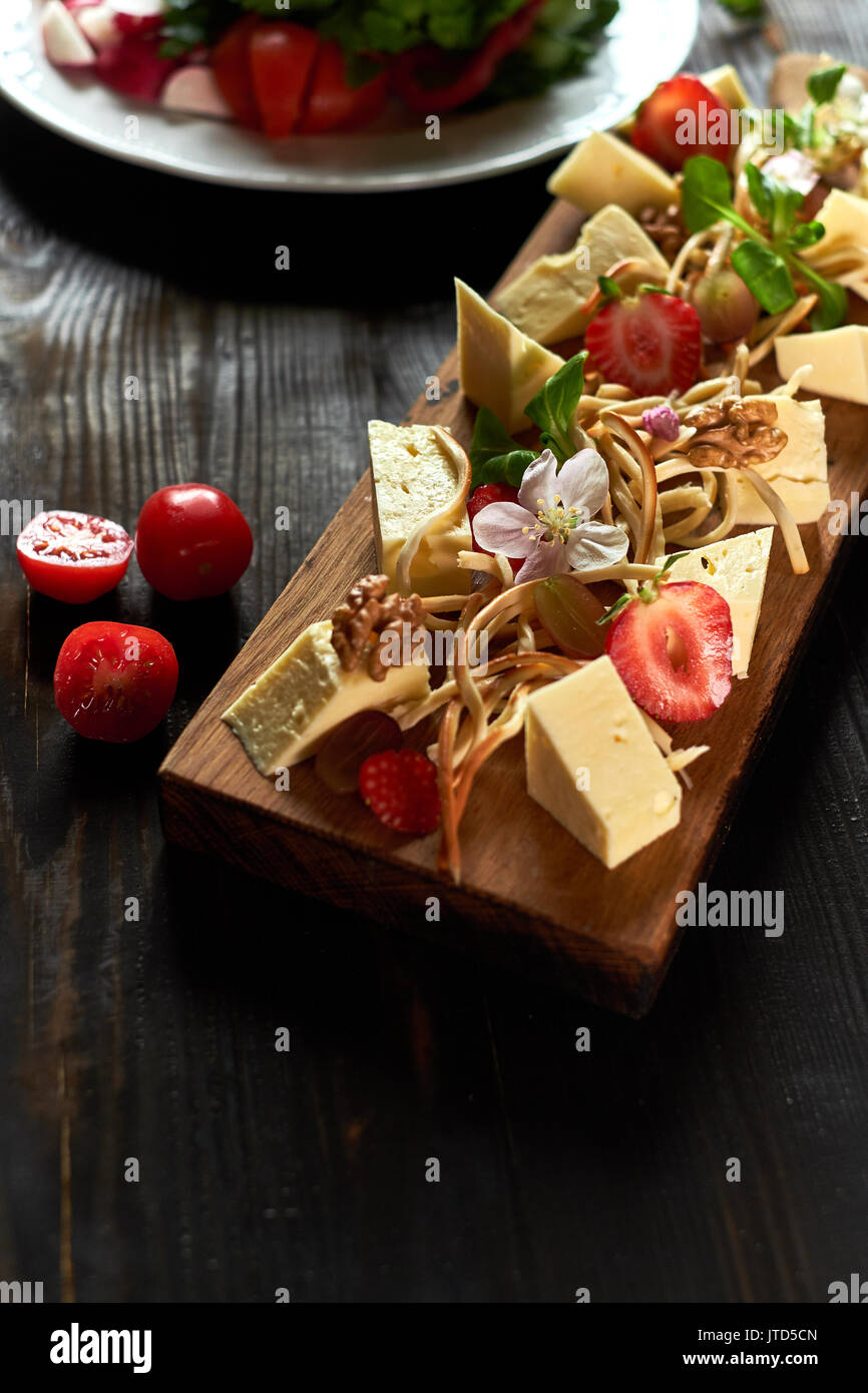 Pieces of cheese on a board with vegetables hd Stock Photo - Alamy