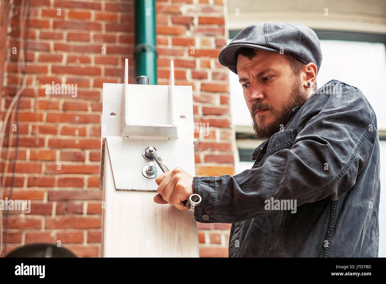 A young man with a beard builder in a construction black uniform, a ...