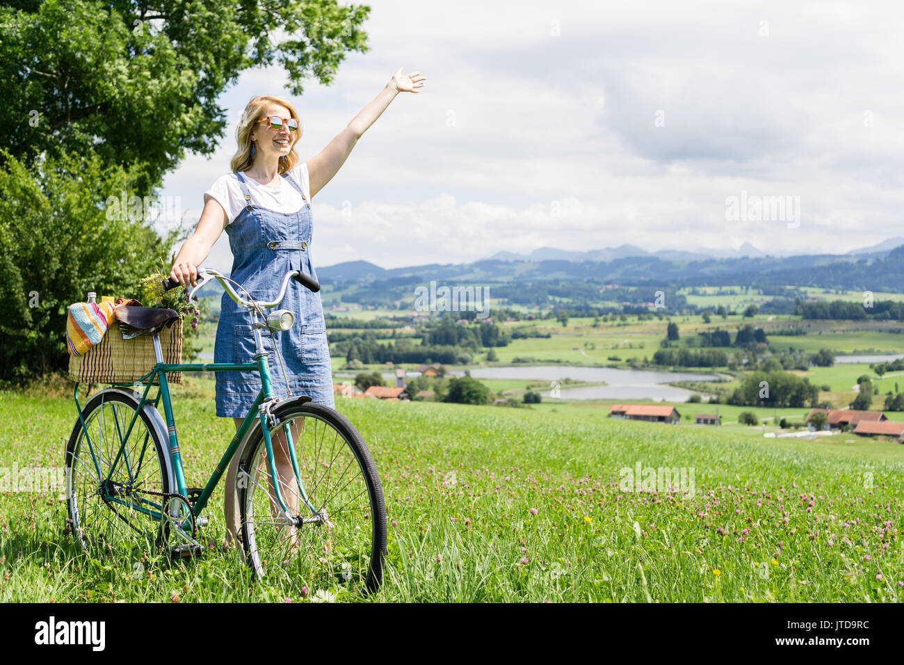 Woman walking with retro bicycle. Waving with raised arm Stock Photo ...