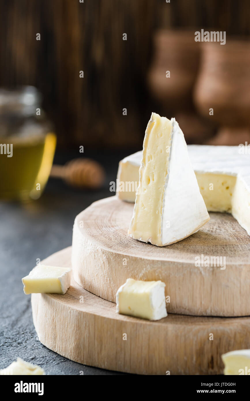 Soft cheese brie sliced on wooden cuts with honey on dark rustic ...