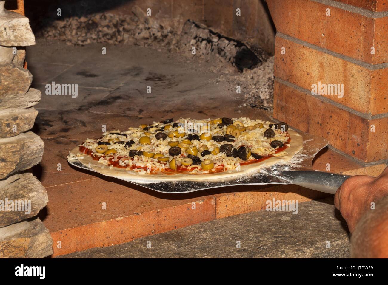 Domestic production of pizza.The man puts pizza in a stone oven Stock ...