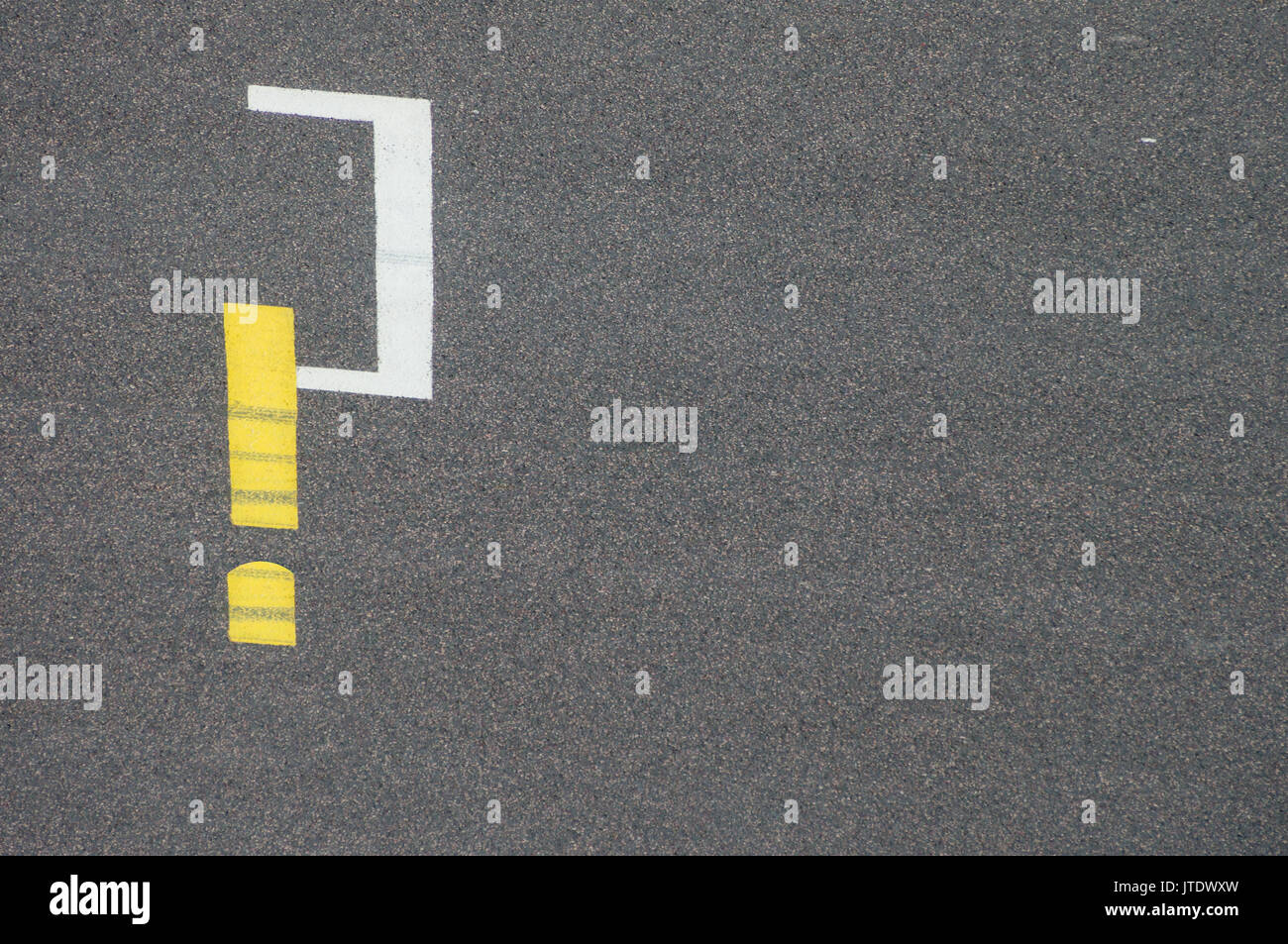 Question mark painted in yellow and white on a road. Signifies the ...