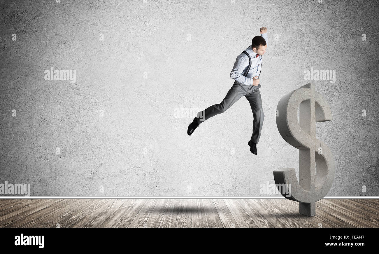 Determined banker man in empty concrete room breaking dollar figure ...