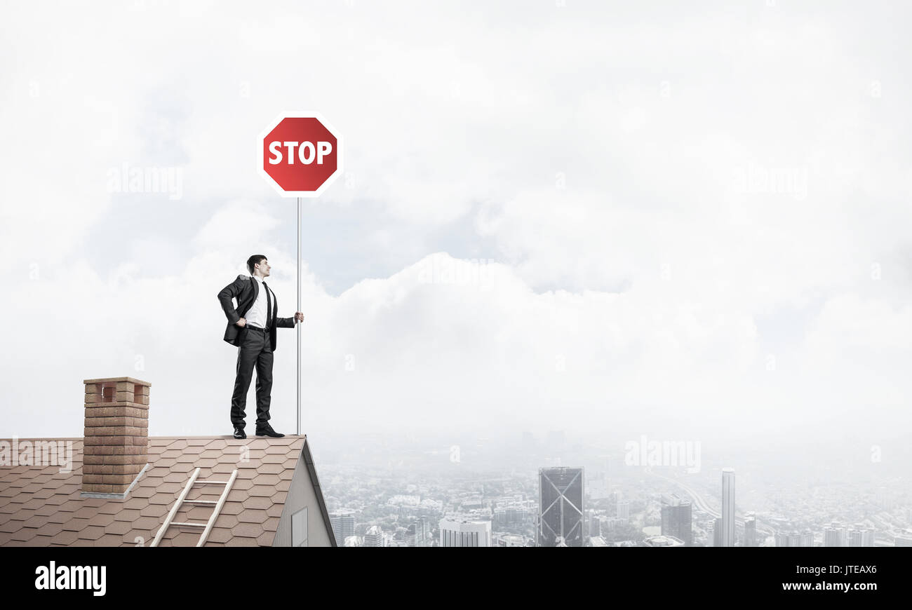 Caucasian businessman on brick house roof showing stop road sign Stock ...