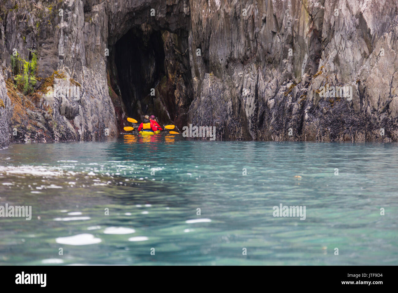 Kayakers at the entry of a little Cave, Aialik Bay, Kenai Peninsula ...