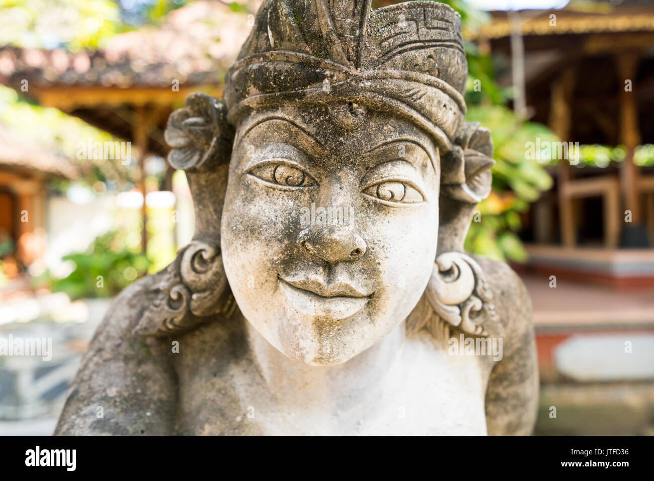 Detail of face - Balinese stone sculpture of a musician in front of ...