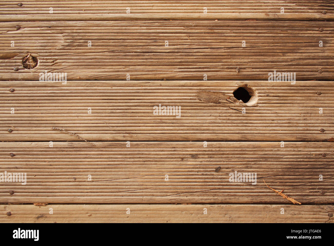 Grooved timber decking laid in a horizontal pattern with a knot hole on ...