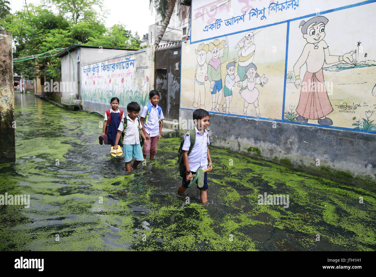 Dhaka, Bangladesh. 8th Aug, 2017. Bangladeshi school children walk on a flooded street as they ...