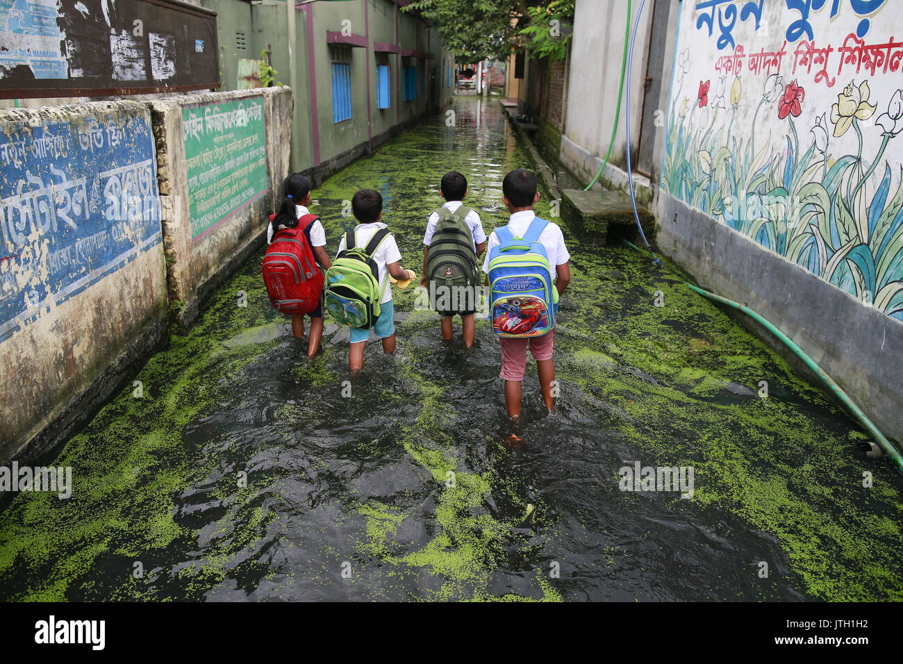Dhaka, Bangladesh. 8th Aug, 2017. Bangladeshi school children walk on a flooded street as they ...