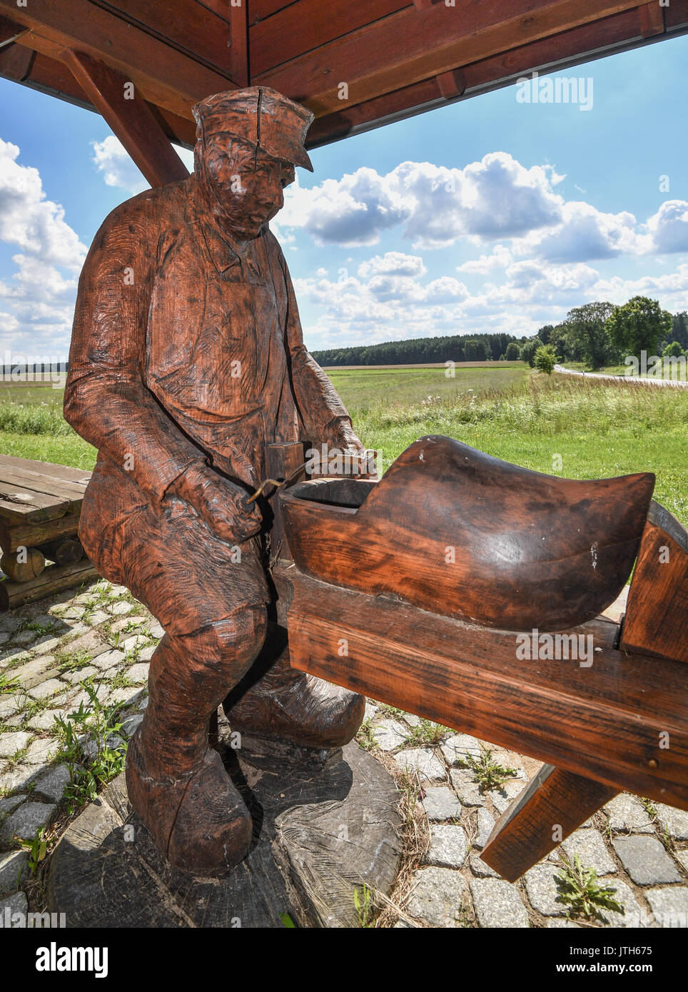 A wooden sculpture of a clog-maker at work outside a workshop in the ...