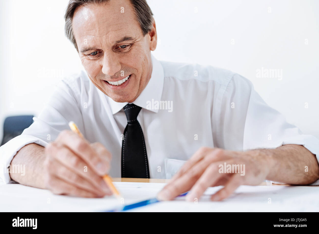 Pleasant man tracing lines on a blueprint Stock Photo - Alamy