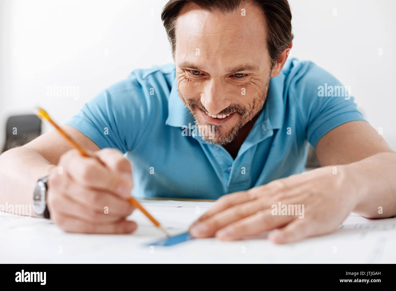Smiling man tracing lines with pencil and ruler Stock Photo - Alamy