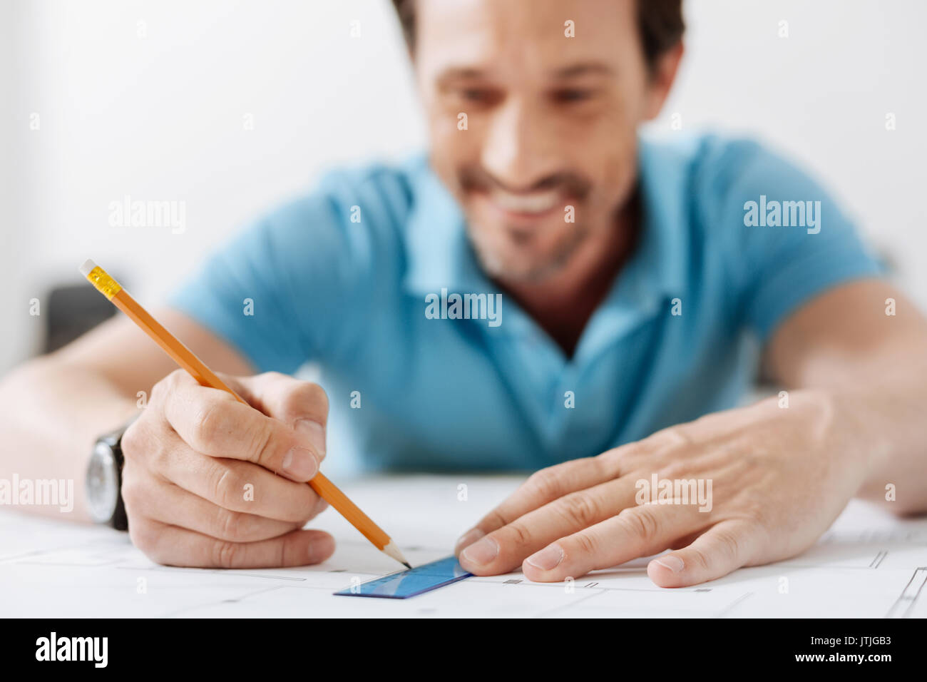 Smiling young man drawing a line on a blueprint Stock Photo - Alamy