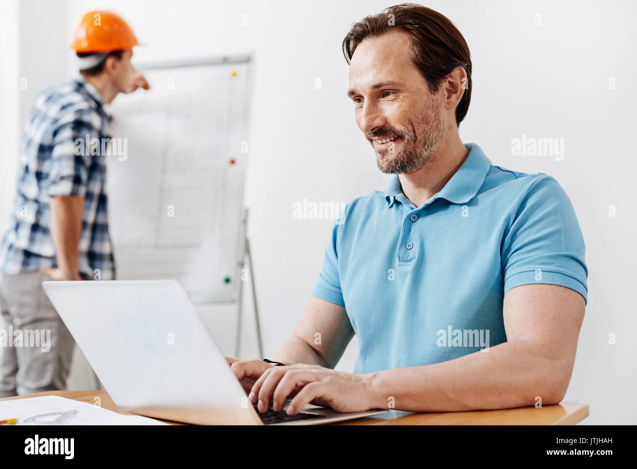 Bristled man typing an email on his laptop Stock Photo - Alamy
