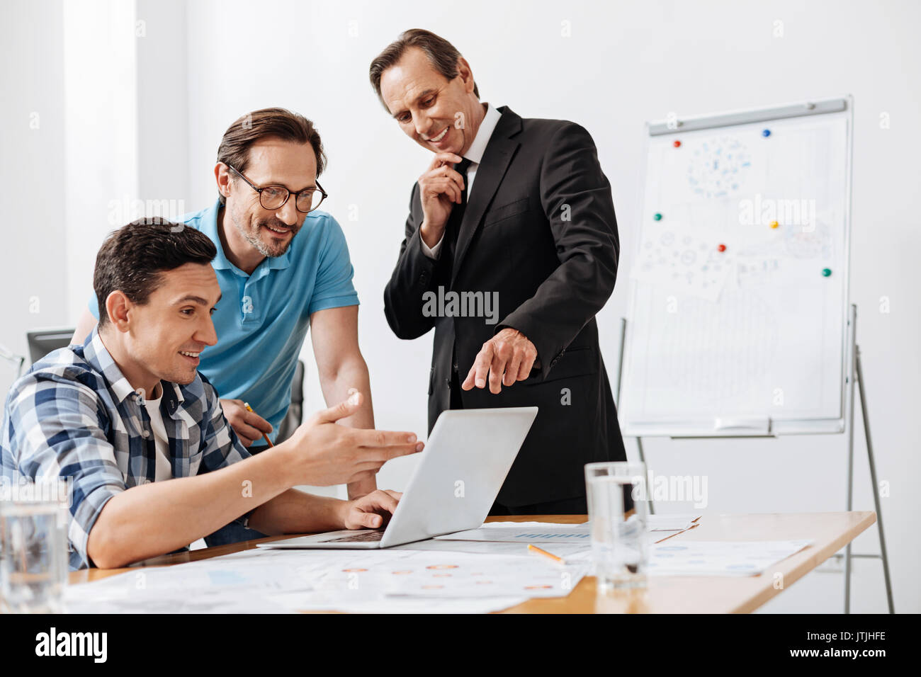 Three employees watching a video on a laptop Stock Photo - Alamy