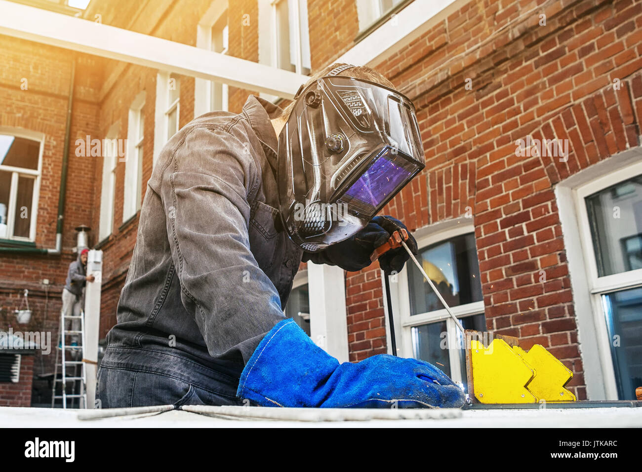 A strong man welder in a construction black overall and welding brush ...