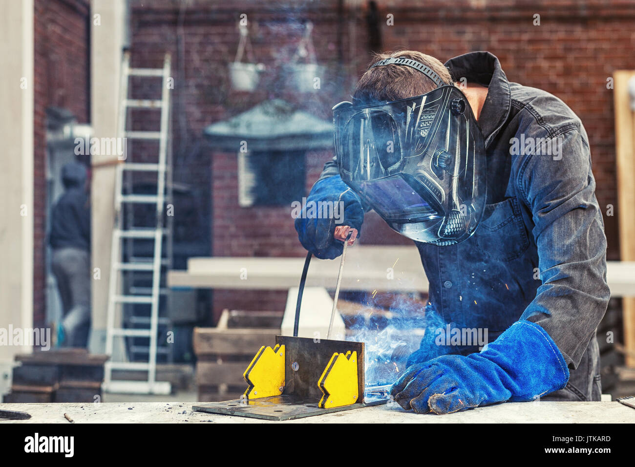 A strong man welder in a construction black overall and welding smear ...