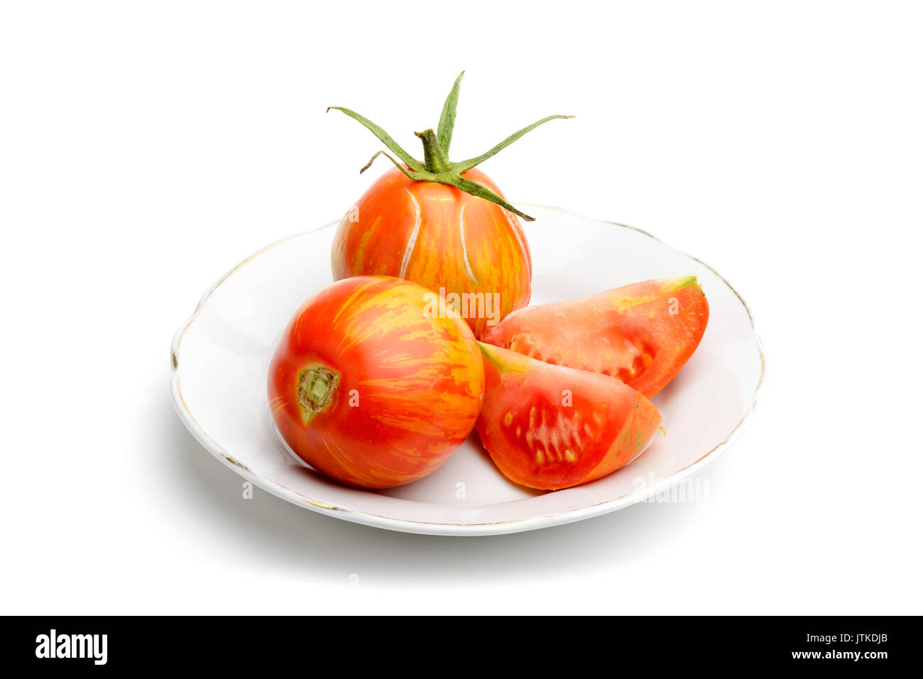 Juicy red zebra tomatoes in a little white porcelain plate, isolated on ...