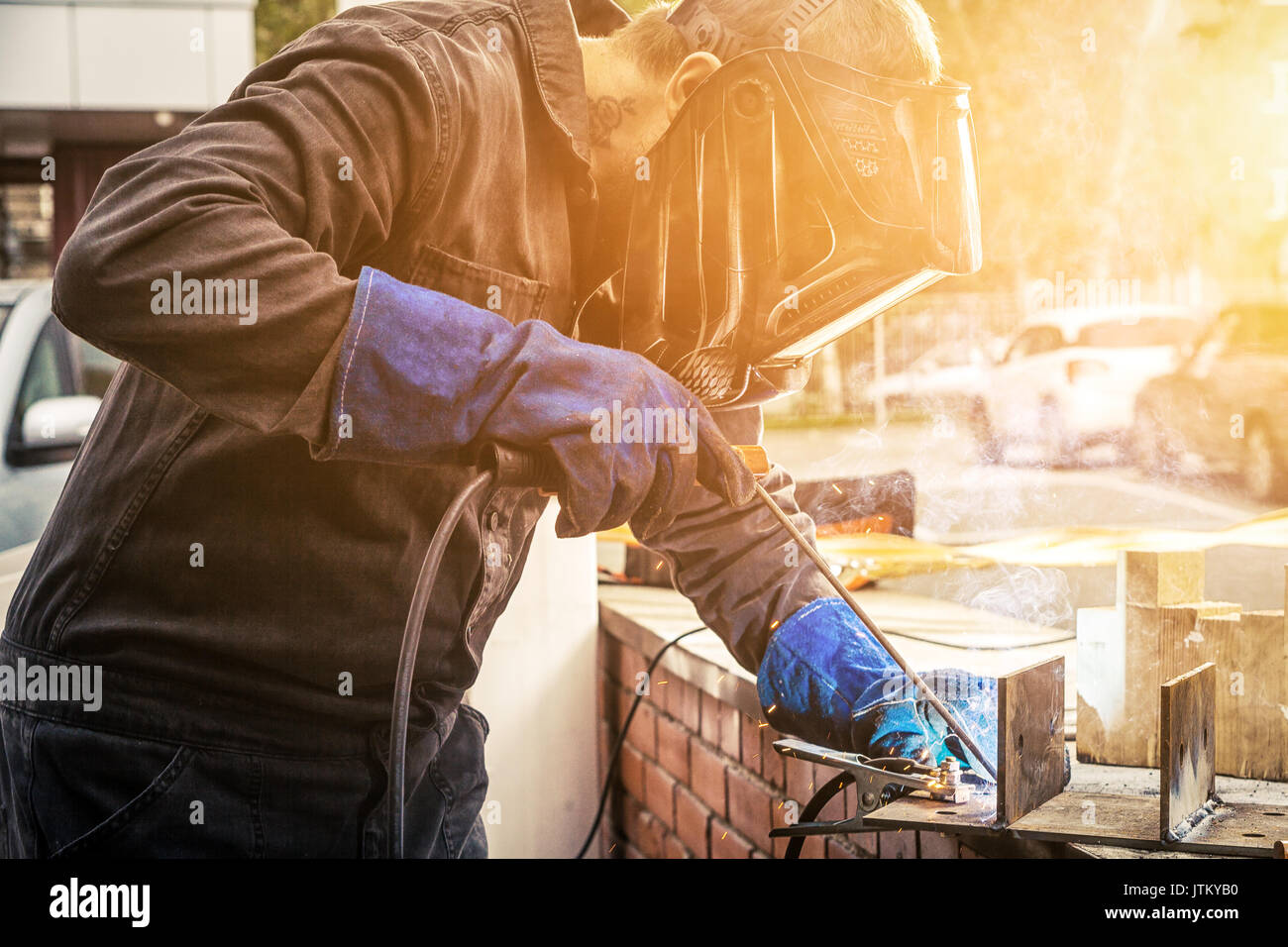 Man welder in a welding mask, building uniform and blue protective ...