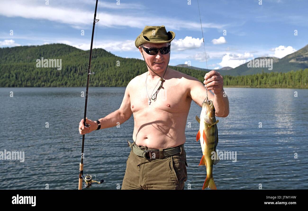 Russian President Vladimir Putin holds a fish he caught fishing during ...