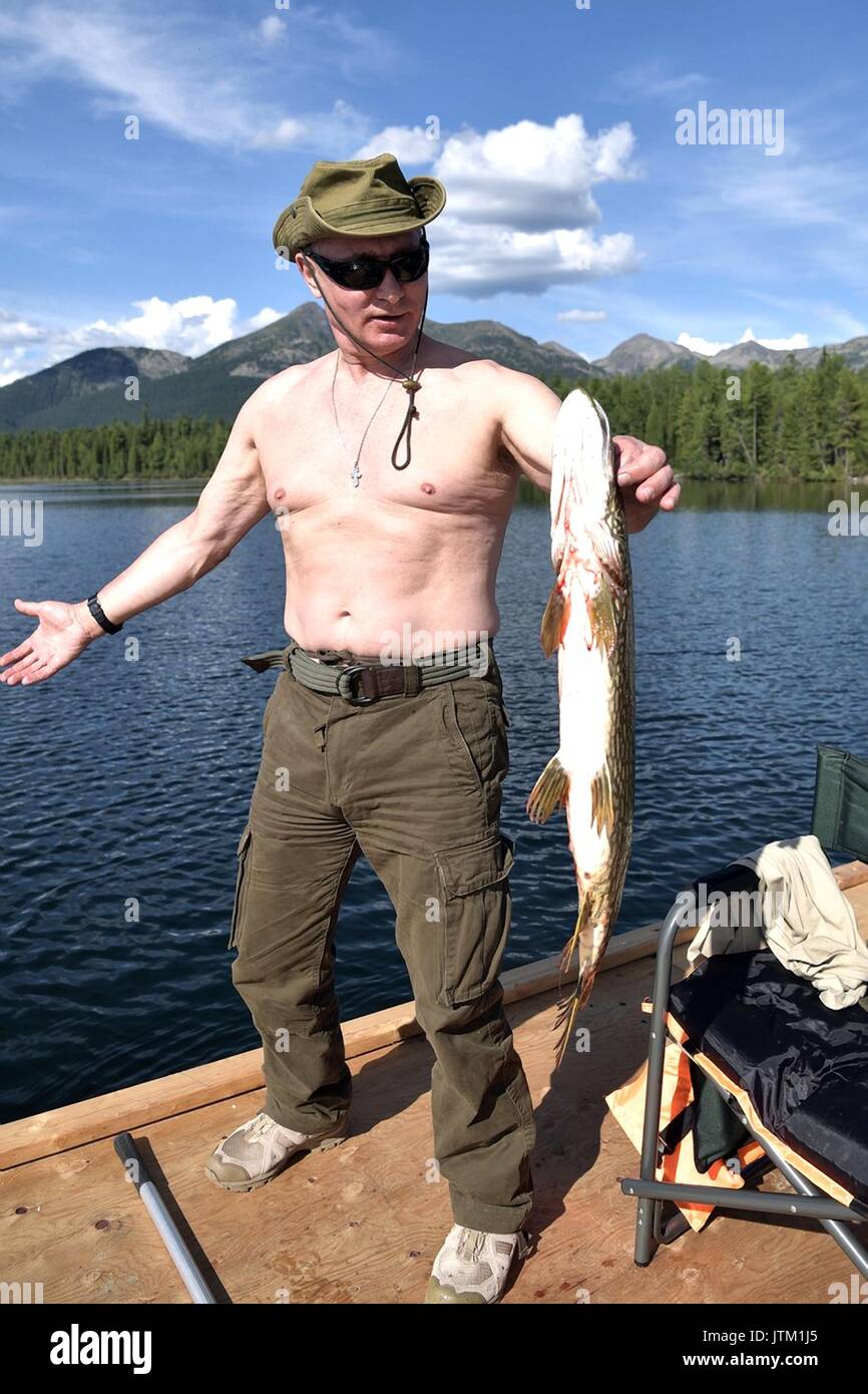 Russian President Vladimir Putin holds a fish he caught fishing during ...