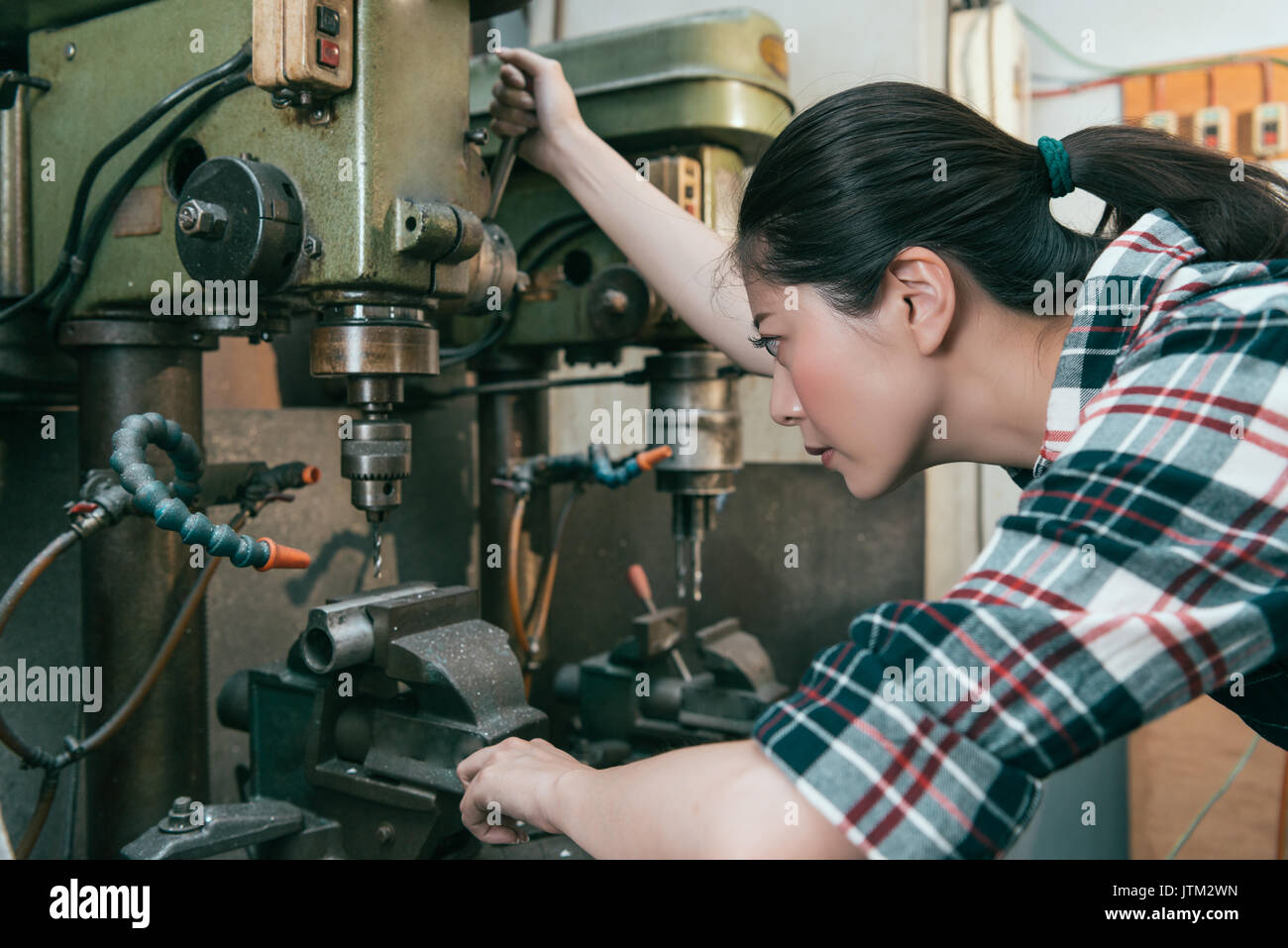seriously milling machine factory female worker looking at steel ...