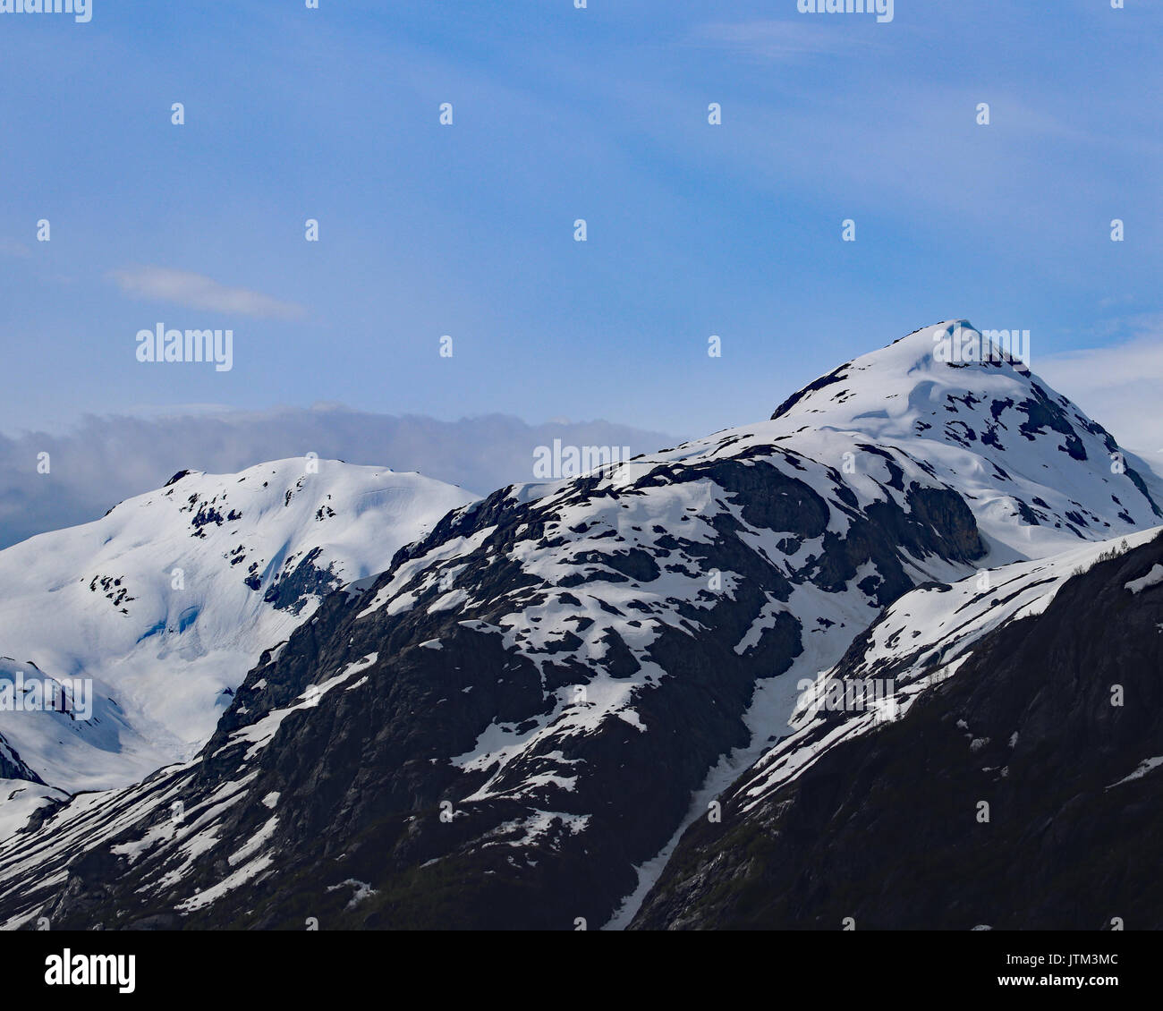 Blue sky and snow capped mountain peaks in rugged Alaska Stock Photo ...