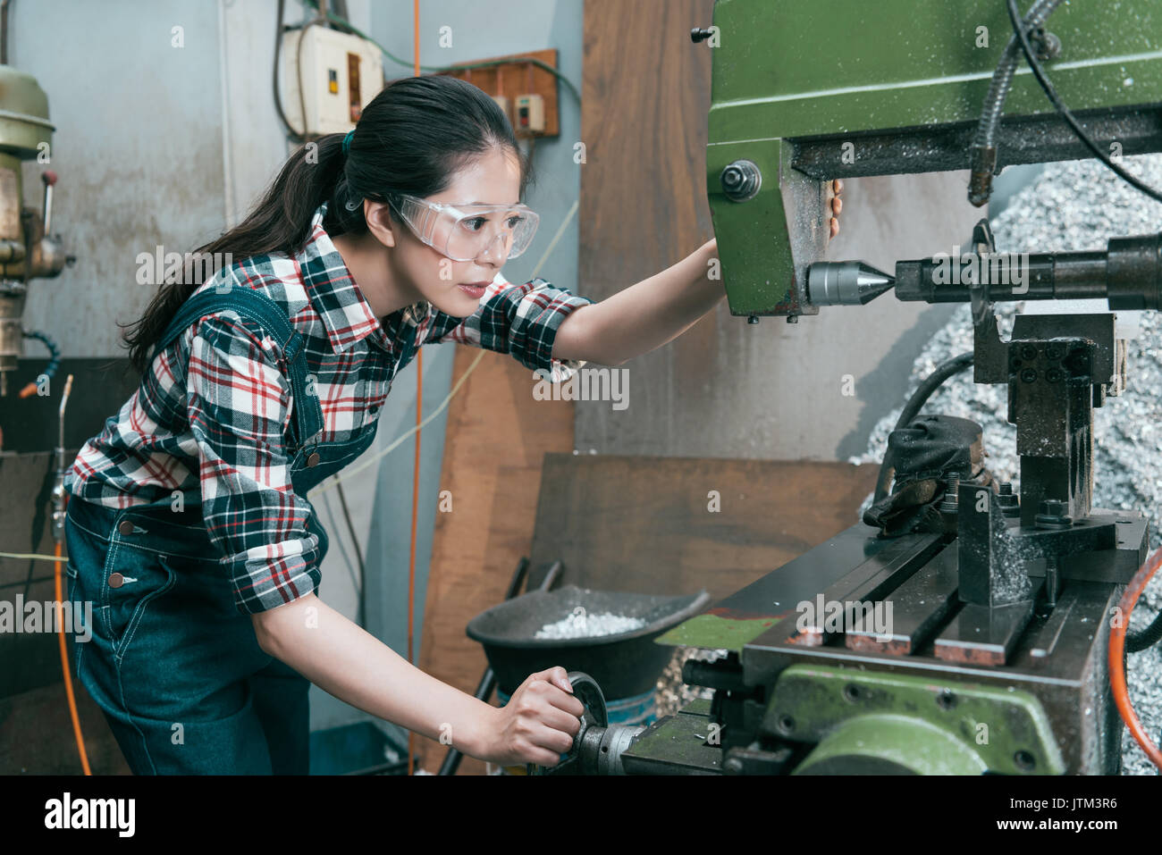 beautiful young lathe company woman worker wearing goggles adjusting ...