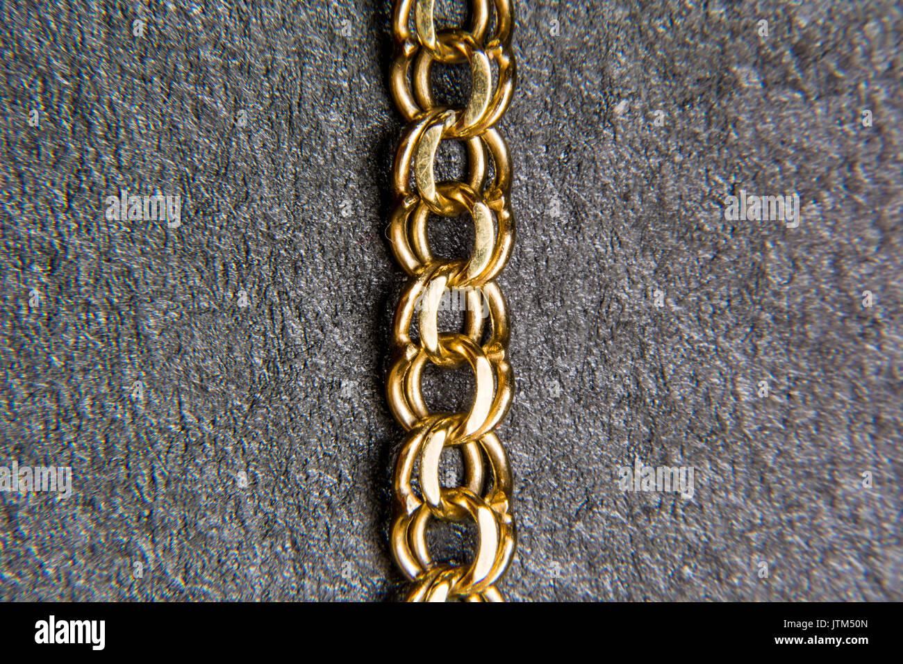 A gold chain on a black textured background Stock Photo - Alamy