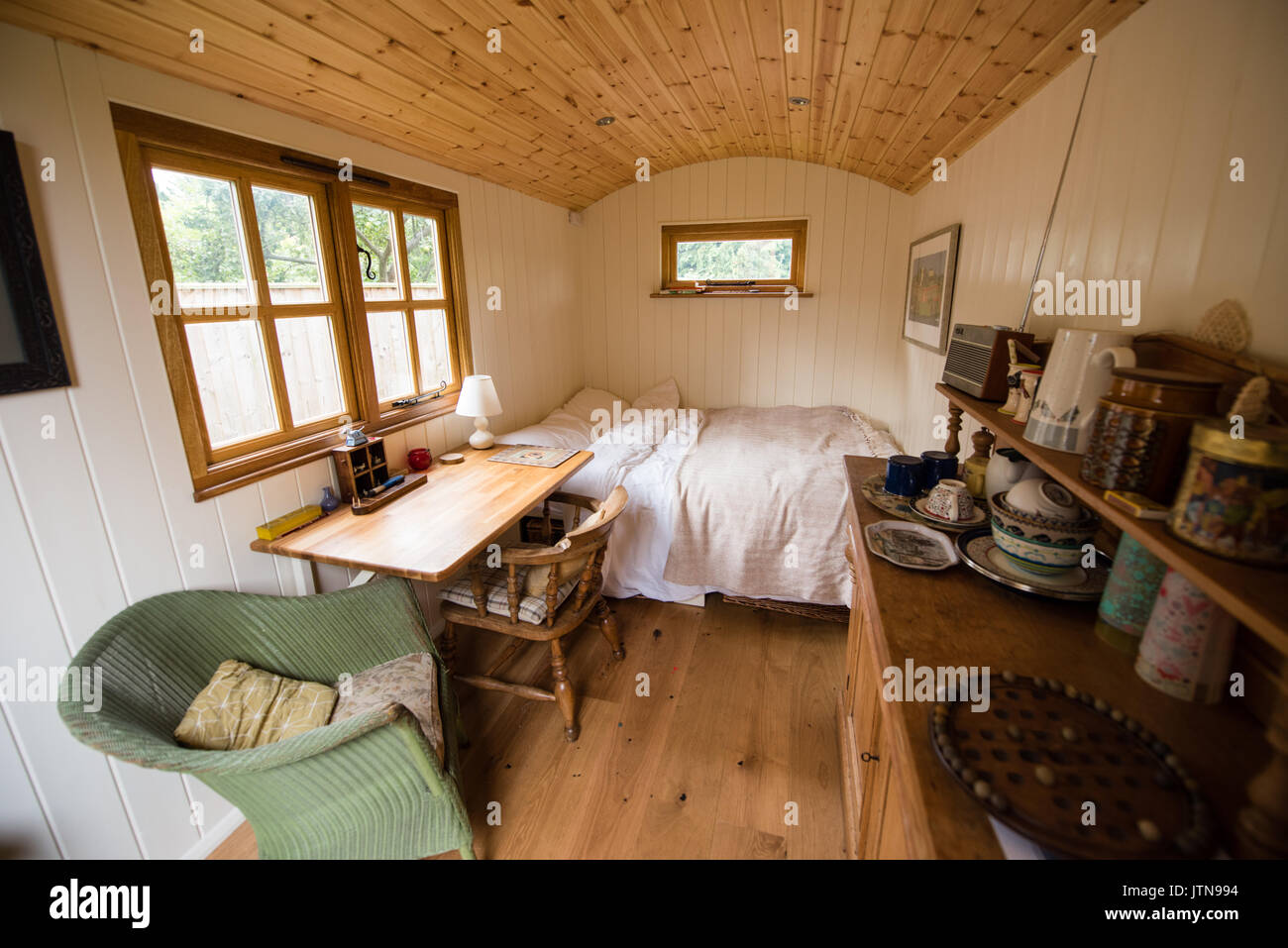 Interior of a cosy Shepherds Hut with a woodburner, bed and antique ...
