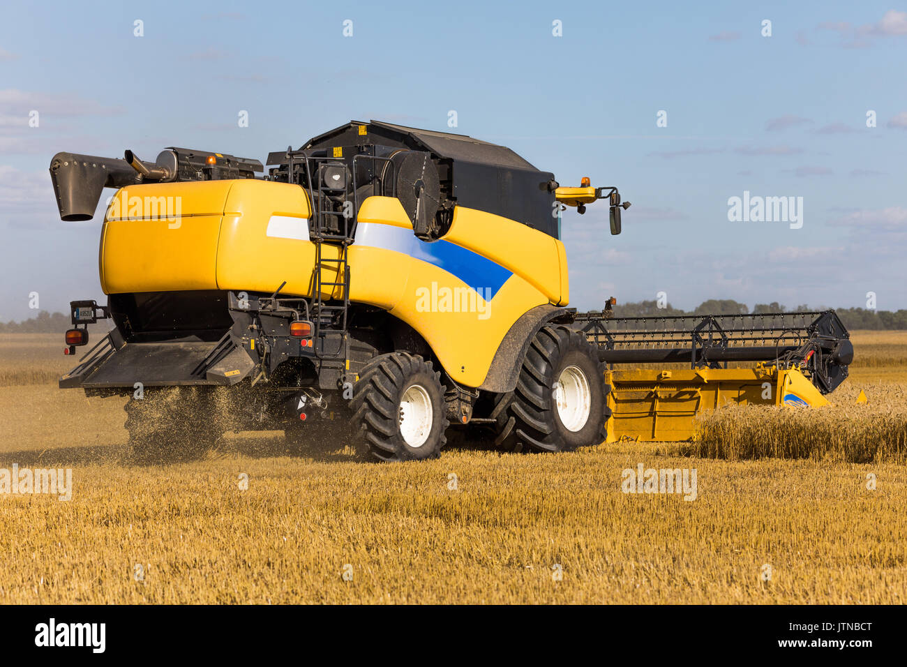 Yellow combine harvester on a wheat field with blue sky Stock Photo - Alamy